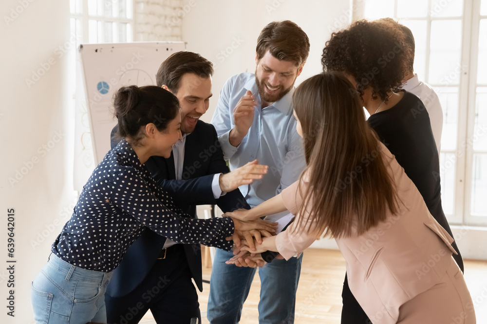 Motivated multiracial businesspeople stack hands in pile participate in ...