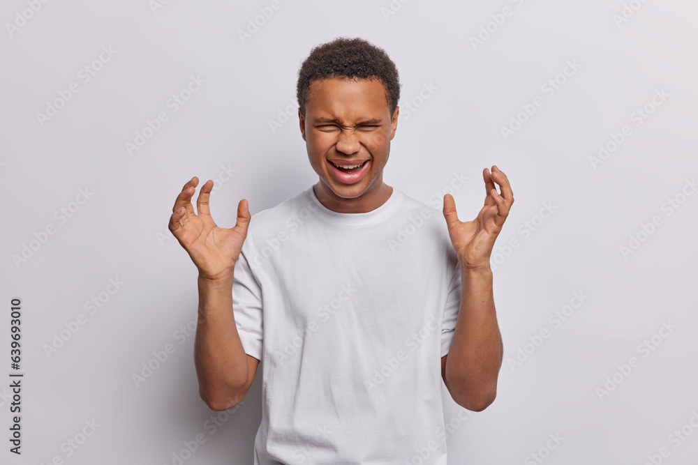 Waist up shot of angry anoyed dark skinned guy gestures actively and ...