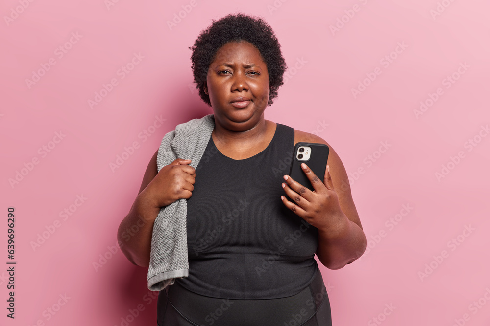 Plus size obese curly woman has discontent expression wears black t ...