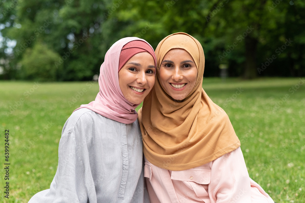 Portrait of two cute young Muslim women in hijabs looking and smiling directly at the camera ...