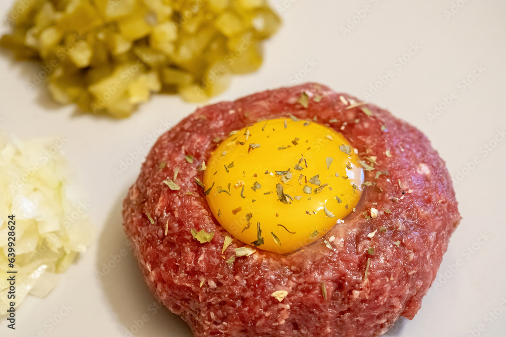 Fresh delicious beef tartare served with a raw egg, cut onions and ...