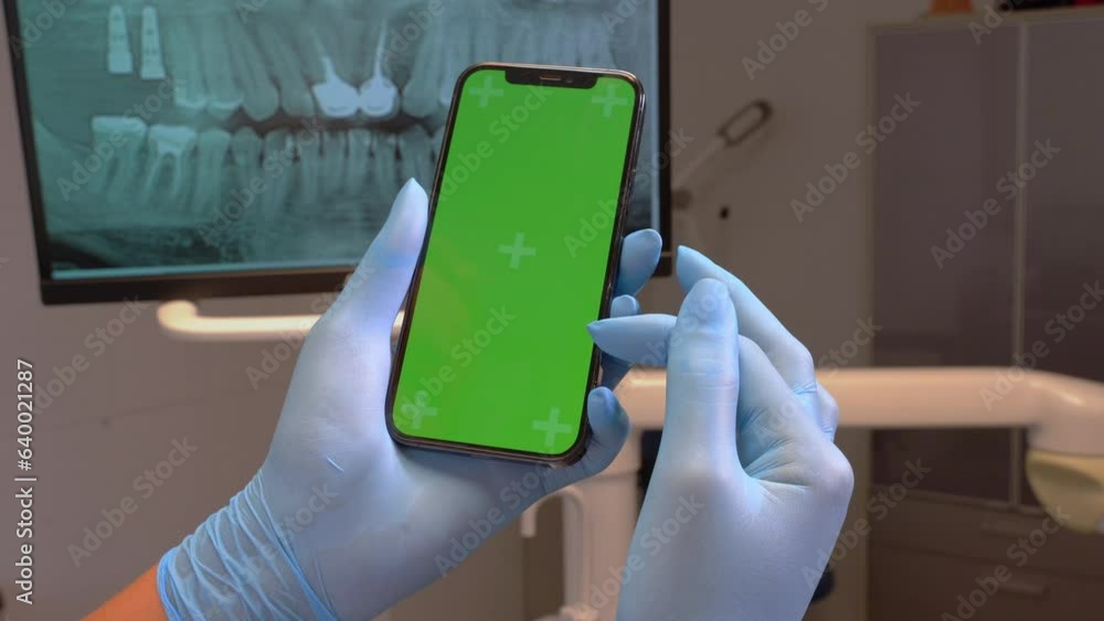 Closeup dentist hands sterile glove hold green screen cellphone at ...