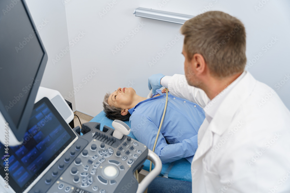 Adult woman having thyroid exam with ultrasound at doctor's office ...