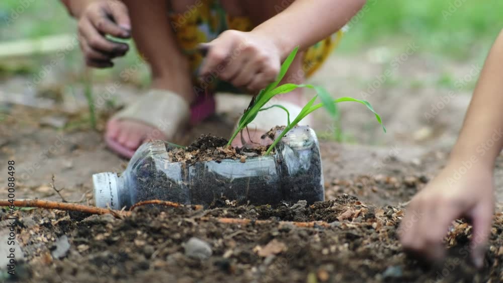 Little girl planting plants in pots from recycled water bottles in the ...