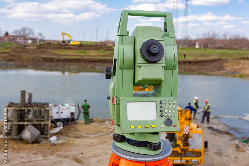 Total station in front of Mobile crane and drilling machine working ...