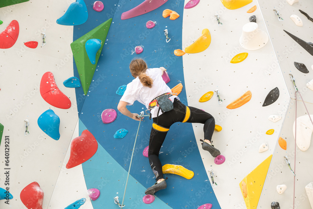 The climber climbs the artificial stone wall with the help of safety ...