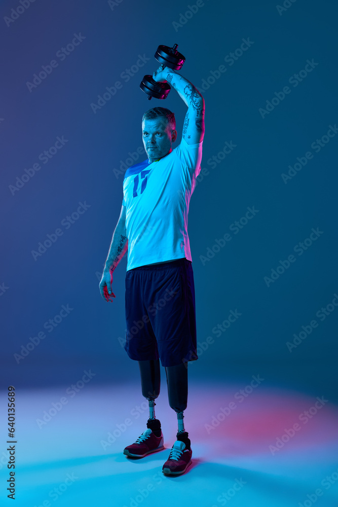 Confident young muscular man prosthetic legs shakes muscles of hands ...