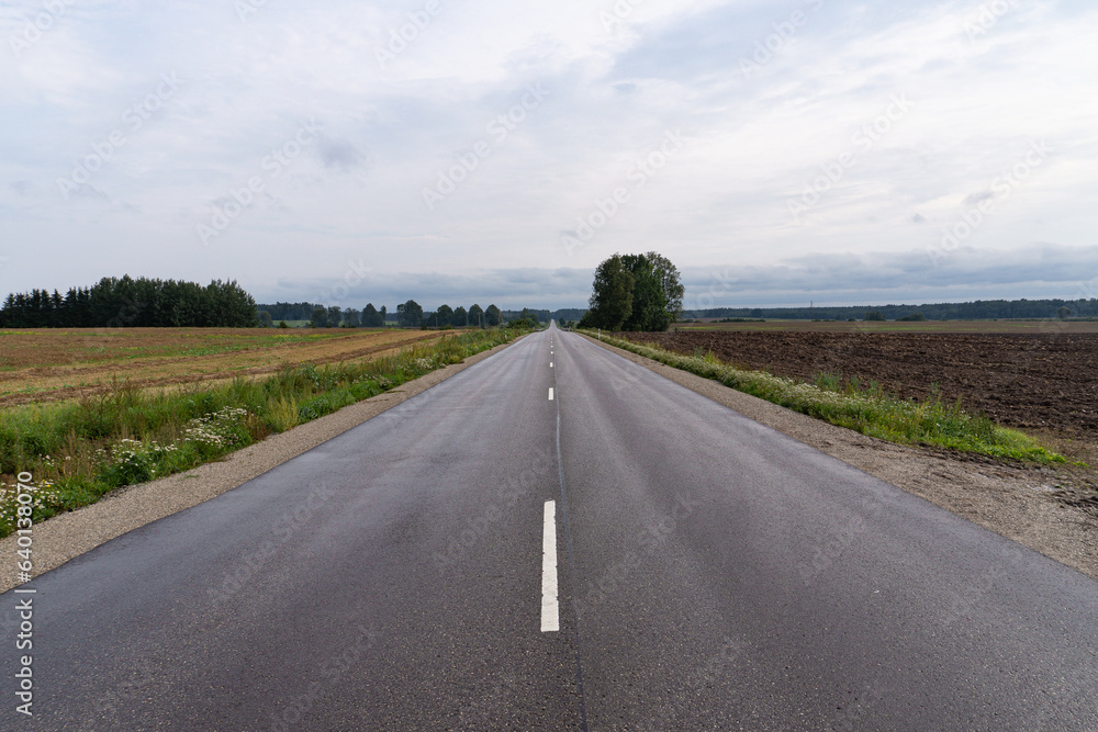 Asphalted road with white interrupted dividing line. A lonely view of ...