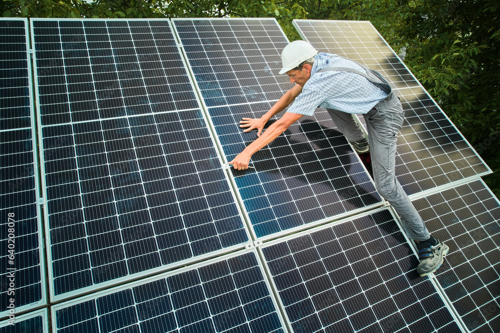 Male worker in safety helmet installing photovoltaic solar panels. Man ...