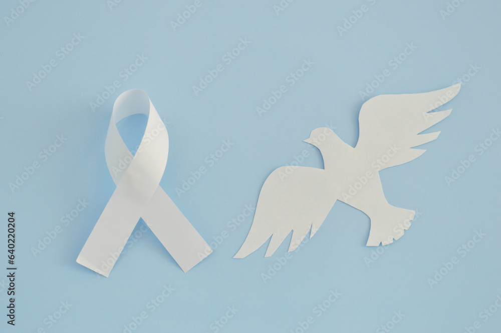 White ribbon as a symbol of peace and paper bird on blue background ...