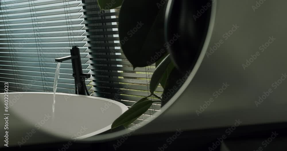 Round mirror with reflection, running water from faucet in bathtub ...