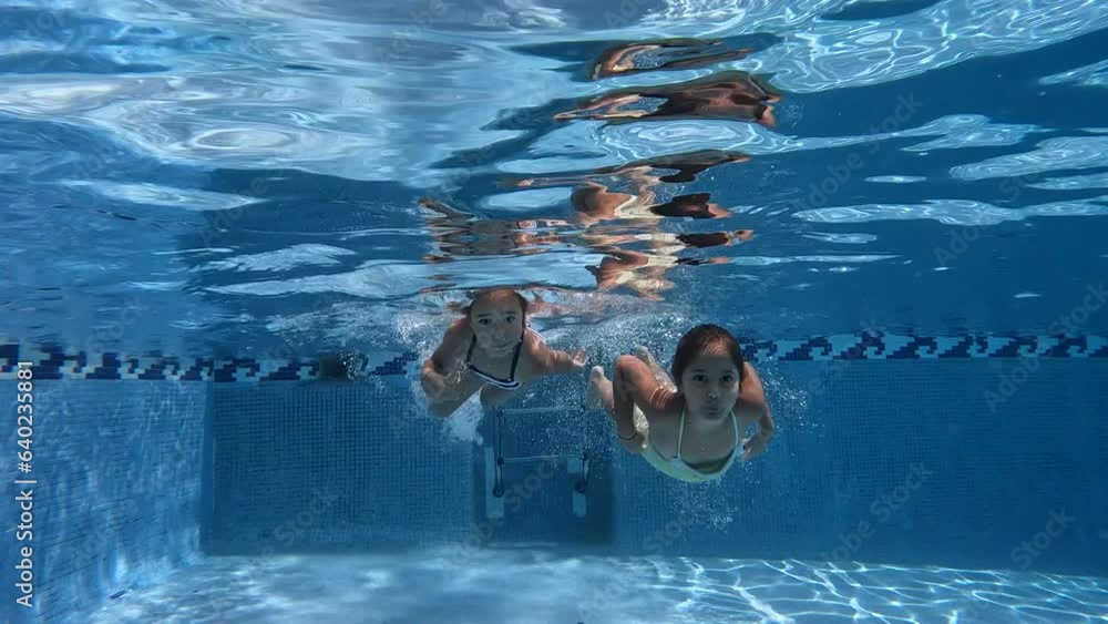 Two girls dive into a pool and wave at the camera. Concept of summer ...