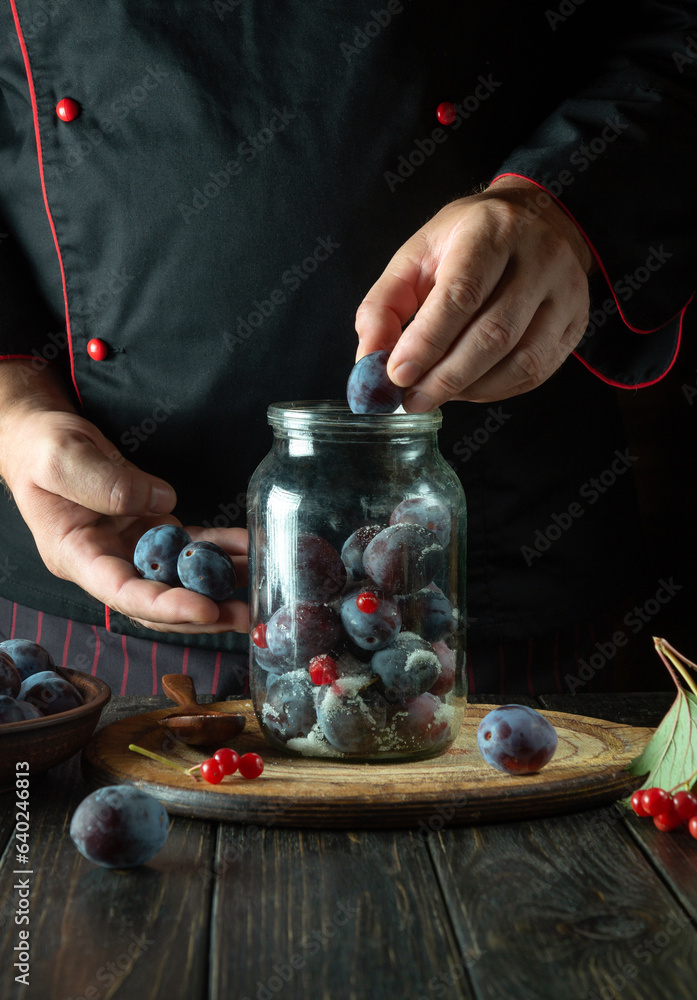 Filling the jar with plums by the hands of the cook. Preparing a sweet ...