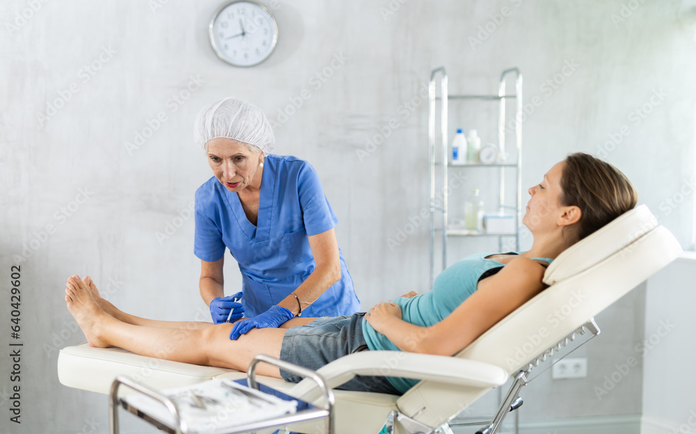 Elderly female doctor performs intra-articular injection treatment of ...
