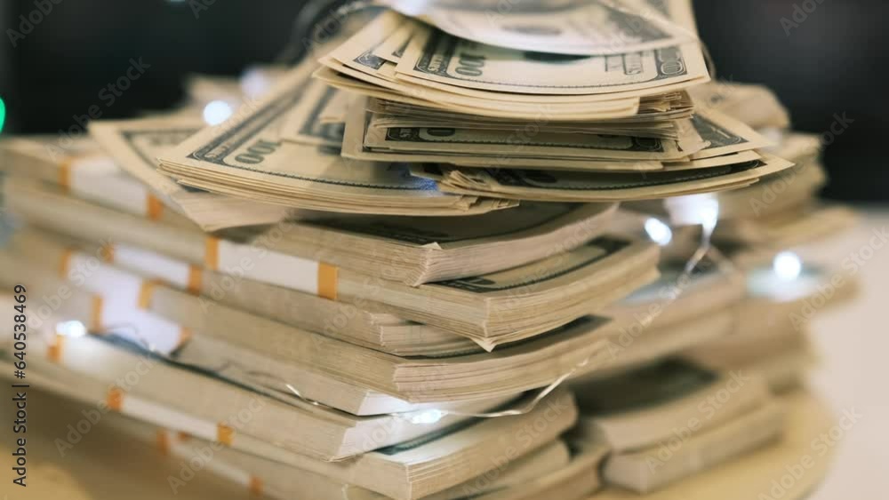 Many 100 dollars paper money cash slowly rotate in glowing lights on ...