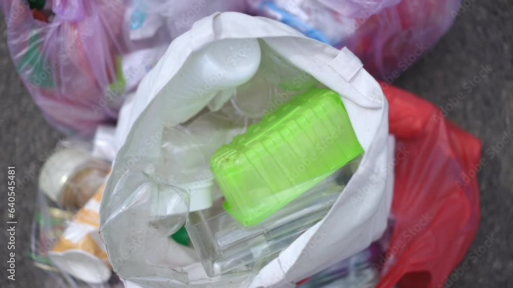 Slim female hand placing empty used plastic cup in garbage bag leaving ...
