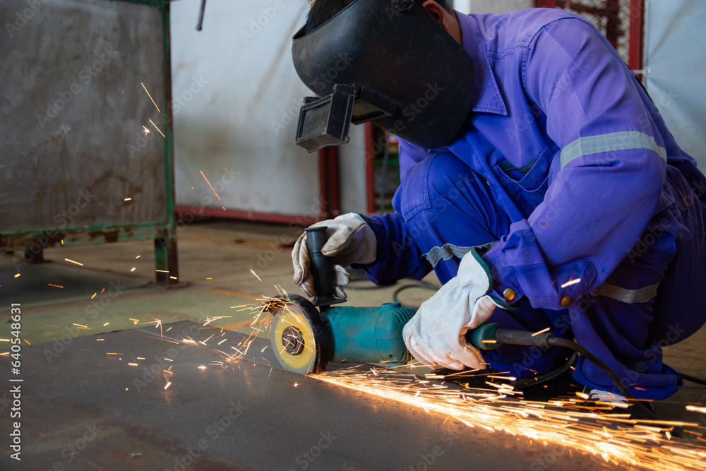 workers cutting metal sheets with electric grinder in the workshop ...