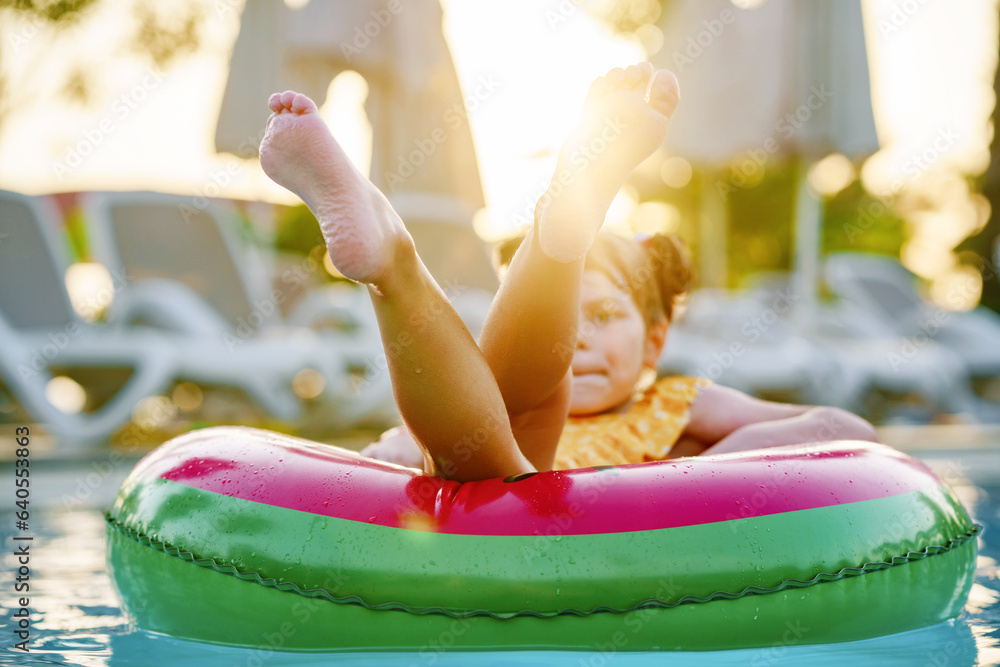 Happy little girl with inflatable toy ring float in swimming pool ...