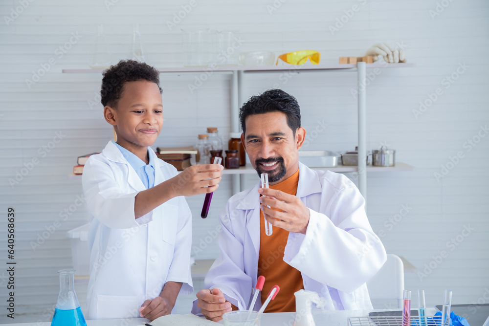 Cheerful African boy primary school students wearing lab coats studying ...