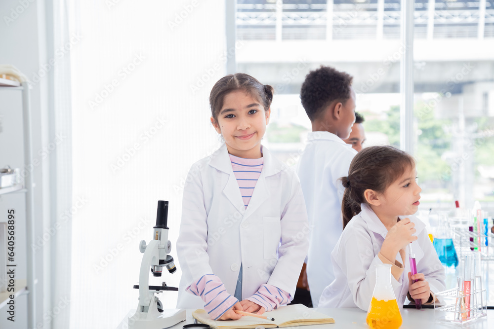 Group of multicultural elementary students wearing lab coats show ...