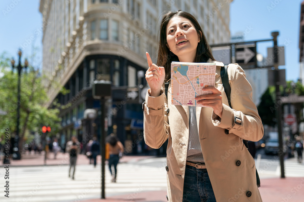 smiling asian korean girl traveler holding map with finger pointing ...