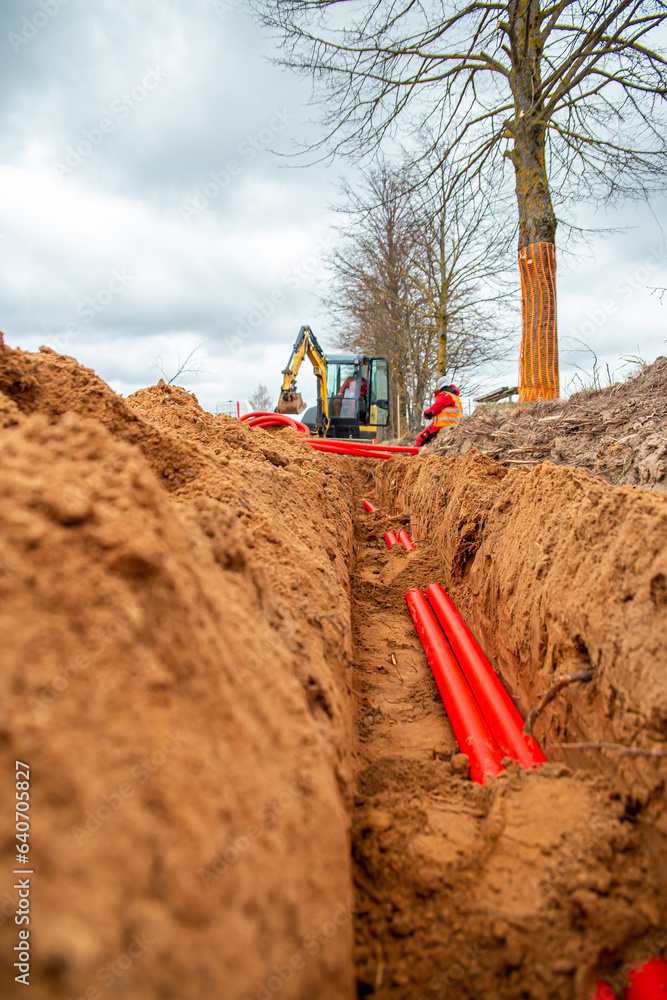 Network cables in red corrugated pipe are buried underground on the ...