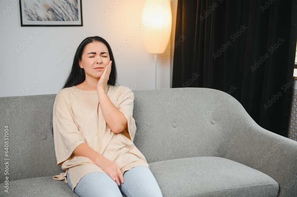 Woman with severe toothache touching her swollen cheek. Young girl ...