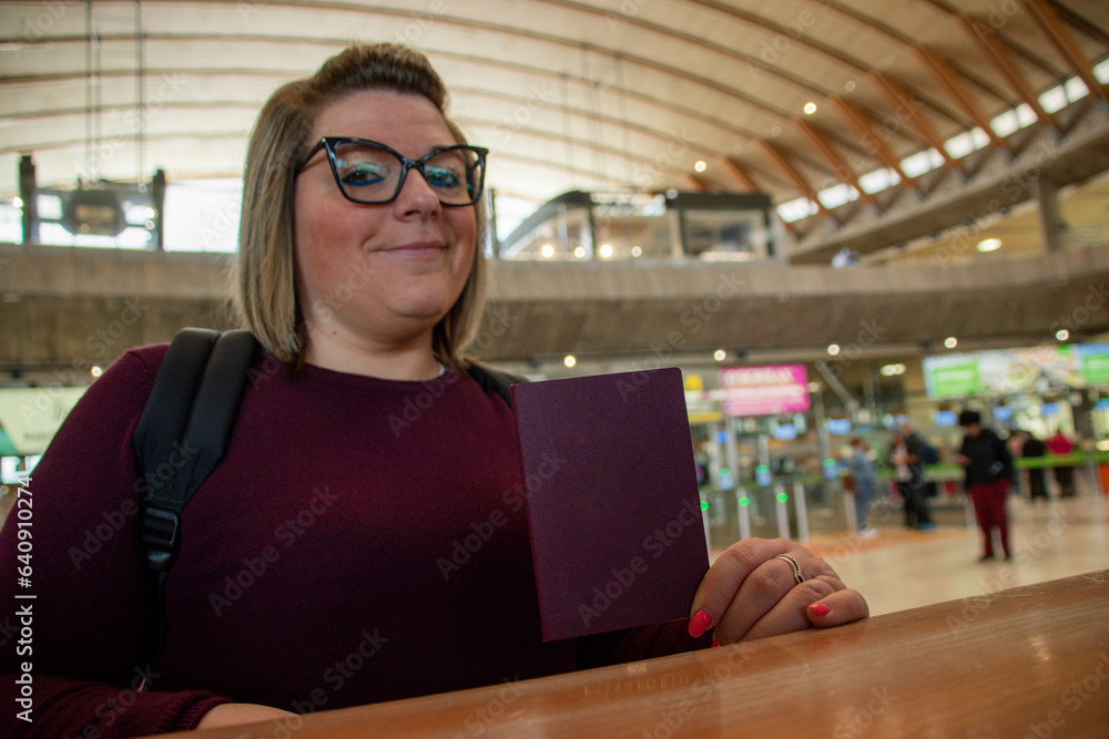Young female traveler shows her passport smiling at the camera ...