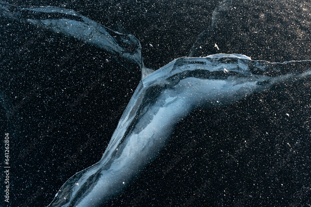 The cracked ice background. Blue transparent ice deep cracks top view ...