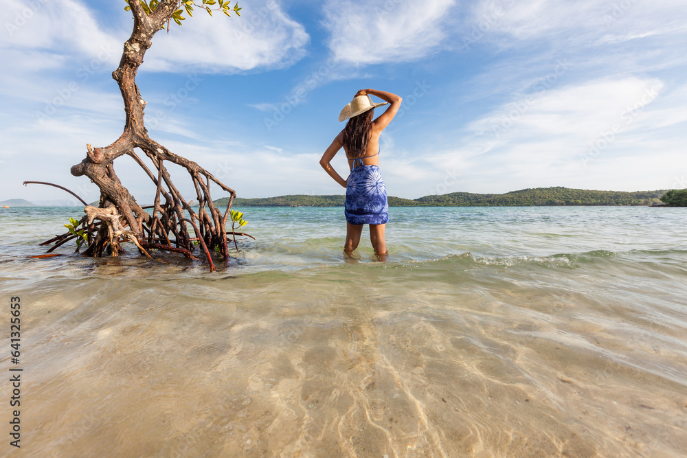 Young Filipino woman walking in the sea and watching the horizon ...