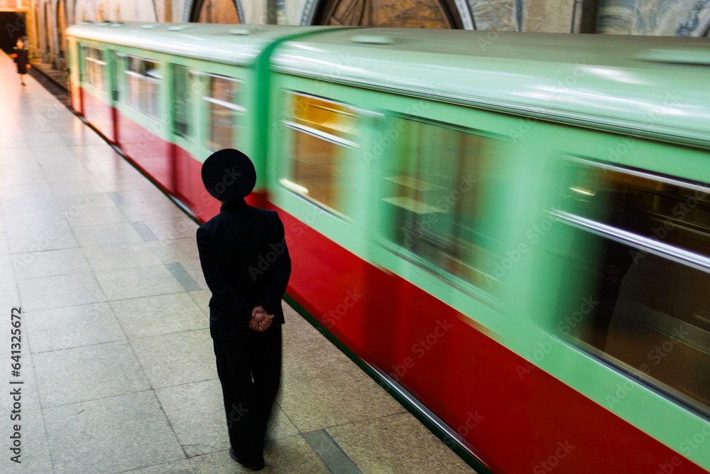 Pyongyang Metro staff watching a departing train from Puhung station ...