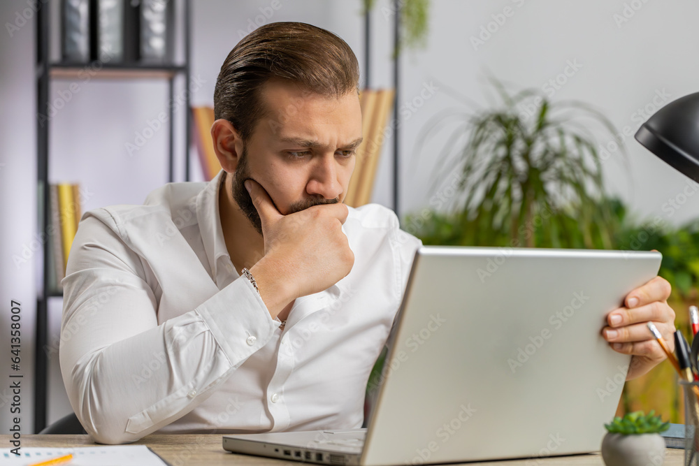 Irritated tired middle eastern business man while working on laptop ...