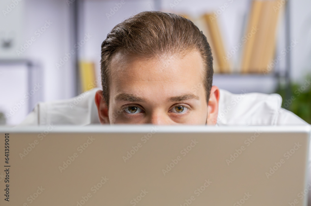 Lebanese confident businessman hiding behind laptop computer, looking ...