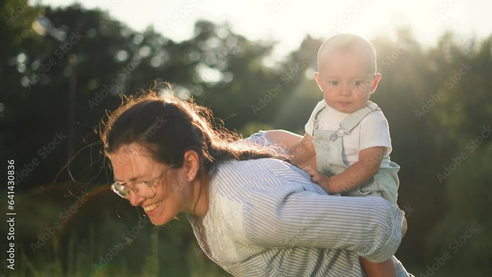 Piggyback. Happy family.Mom plays with baby in park in nature. Kid and ...