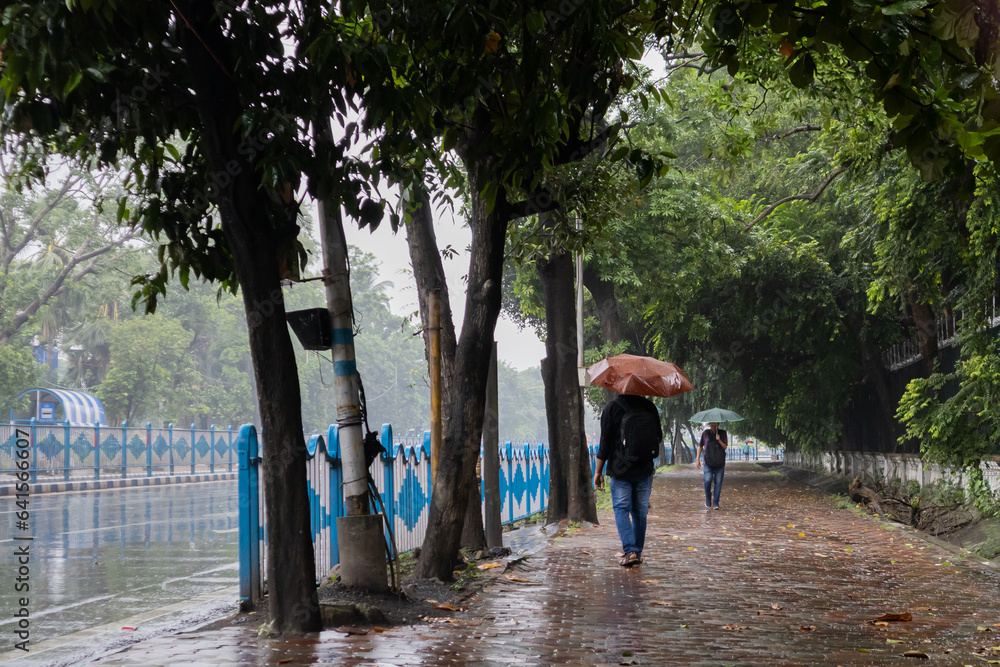 people walking with umbrella on a rain wet foot path and during monsoon ...