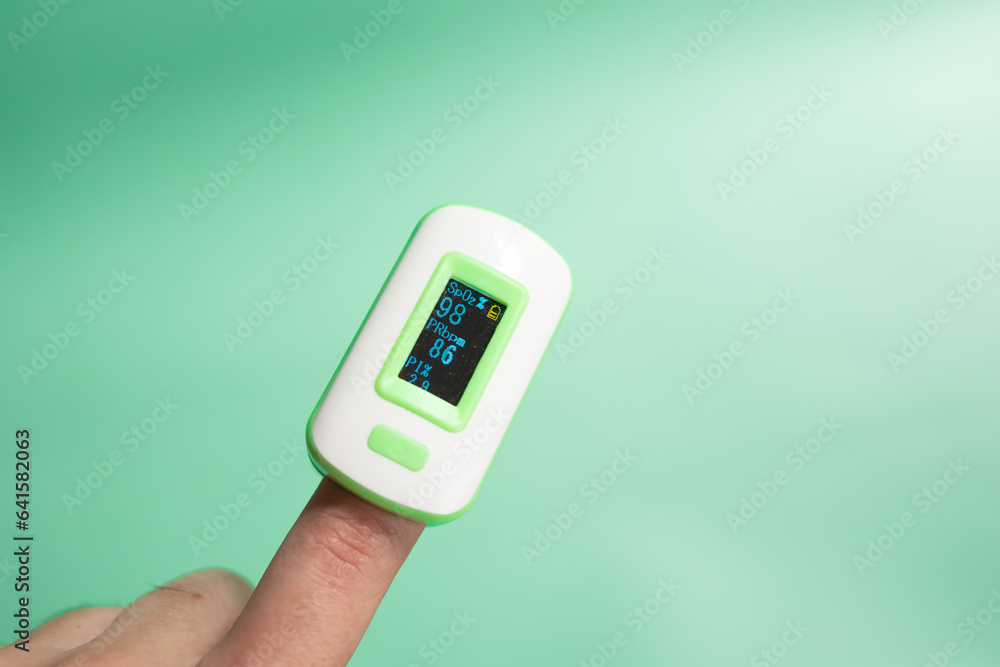 Pulse oximeter on finger showing oxygen saturation and heart rate ...