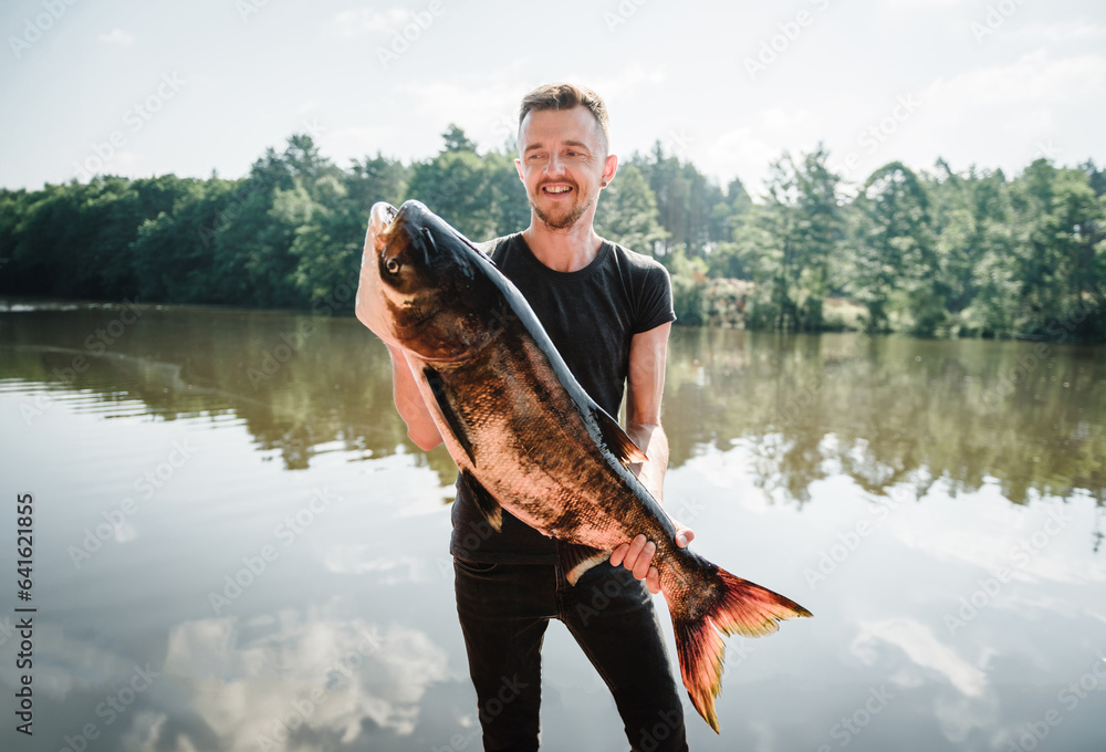 Happy fisherman hold big trophy fish near lake. Success pike fishing ...