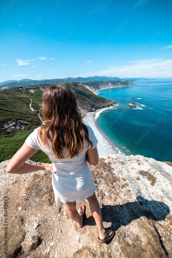Unwind and marvel: Overlooking a heavenly beach, she stands at the cliff's edge, immersed in the ...