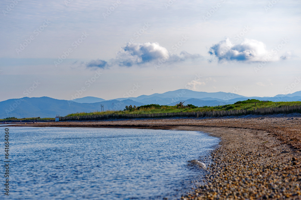 Sand beach in bright sunlight with mountain panorama in the background ...