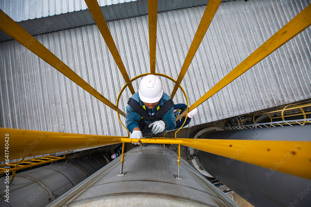 Top view male worker climbs up the ladder inspection stainless tank ...