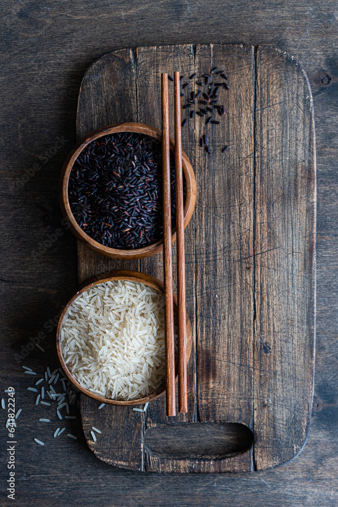 Raw wild black rice and peeled white rice in the bowls with chopsticks ...