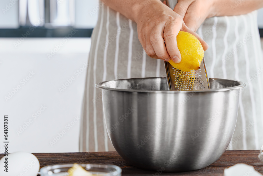 The cook's hands grate the zest of a lemon into a bowl of dough ...