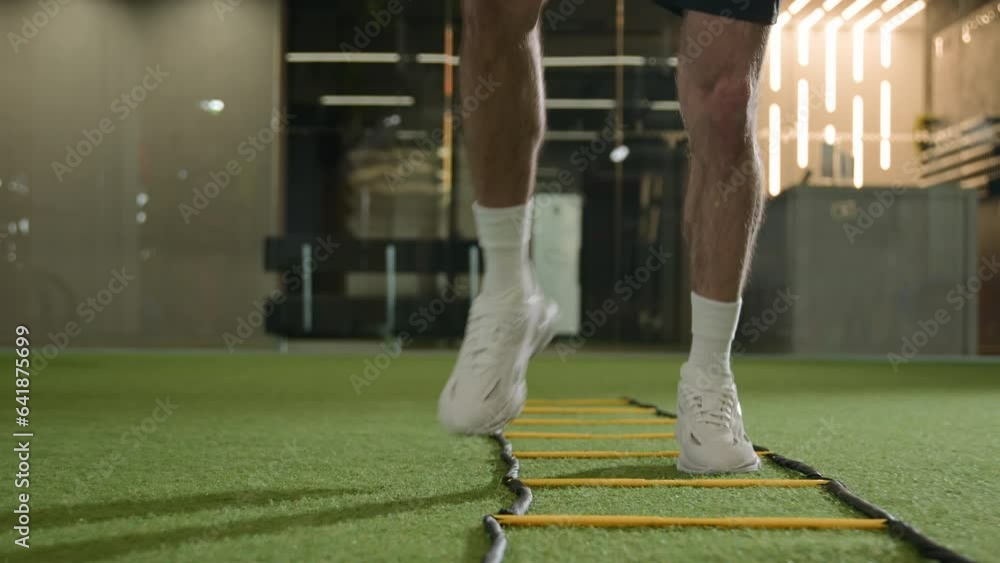 Unknown professional footballer running exercise jumping between ladder ...