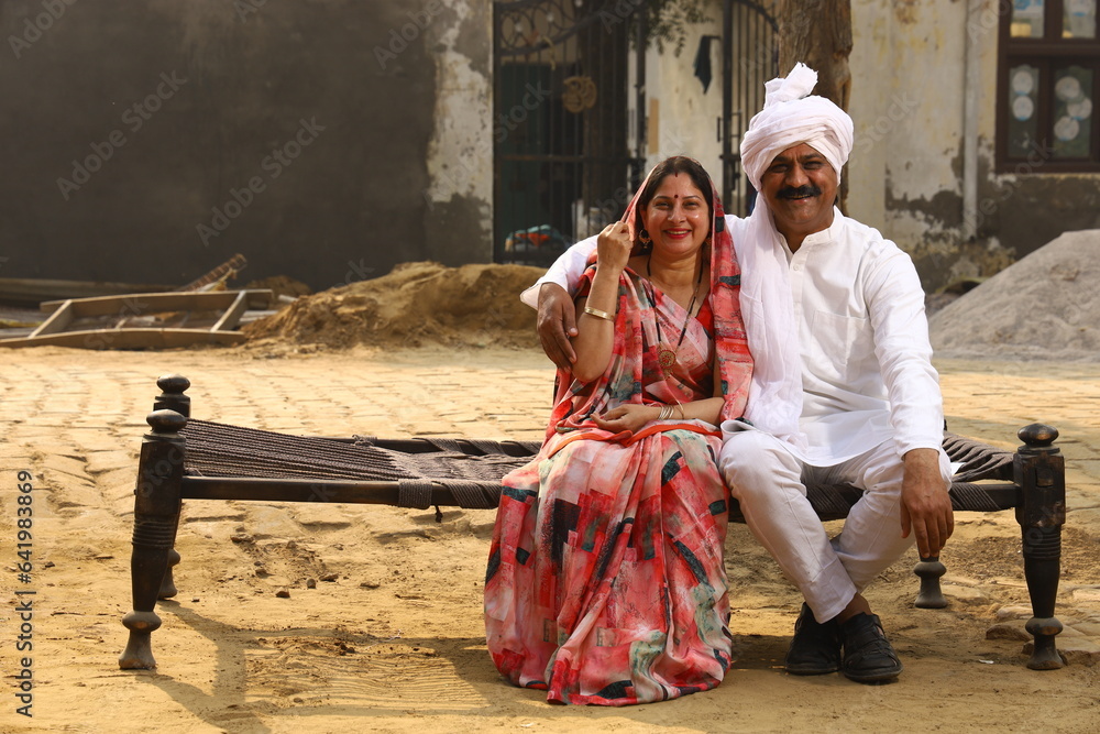 Happy Indian Rural family in village. Husband and wife sitting on cot ...
