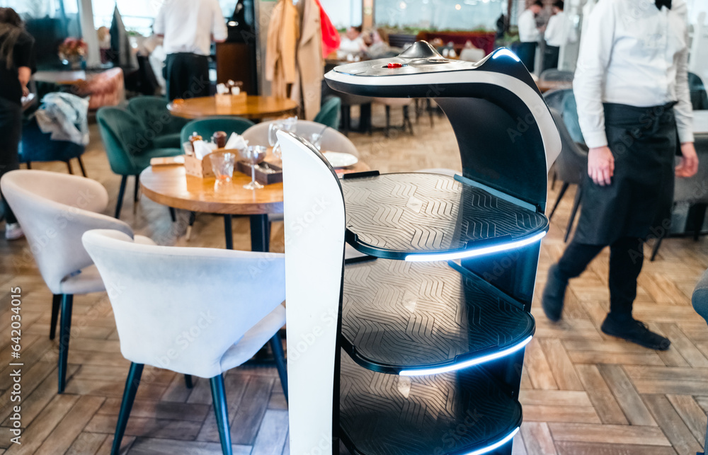 Robot waiter serve food at modern restaurant table.Offering innovation ...