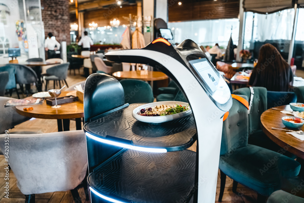 Robot waiter serve food at modern restaurant table.Offering innovation ...