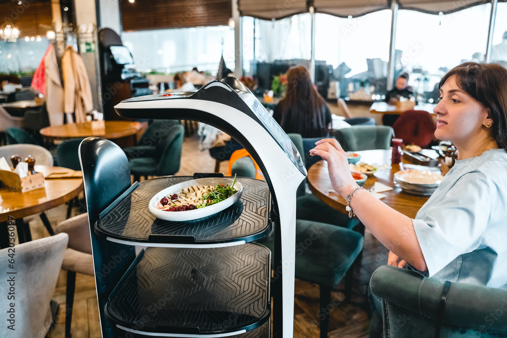 Robot waiter serve food at modern restaurant table.Offering innovation ...