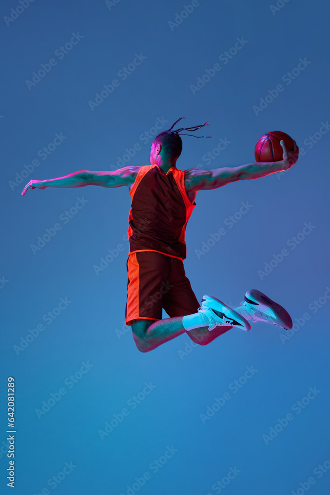 Scoring winning goal. Young man in uniform playing basketball, jumping ...