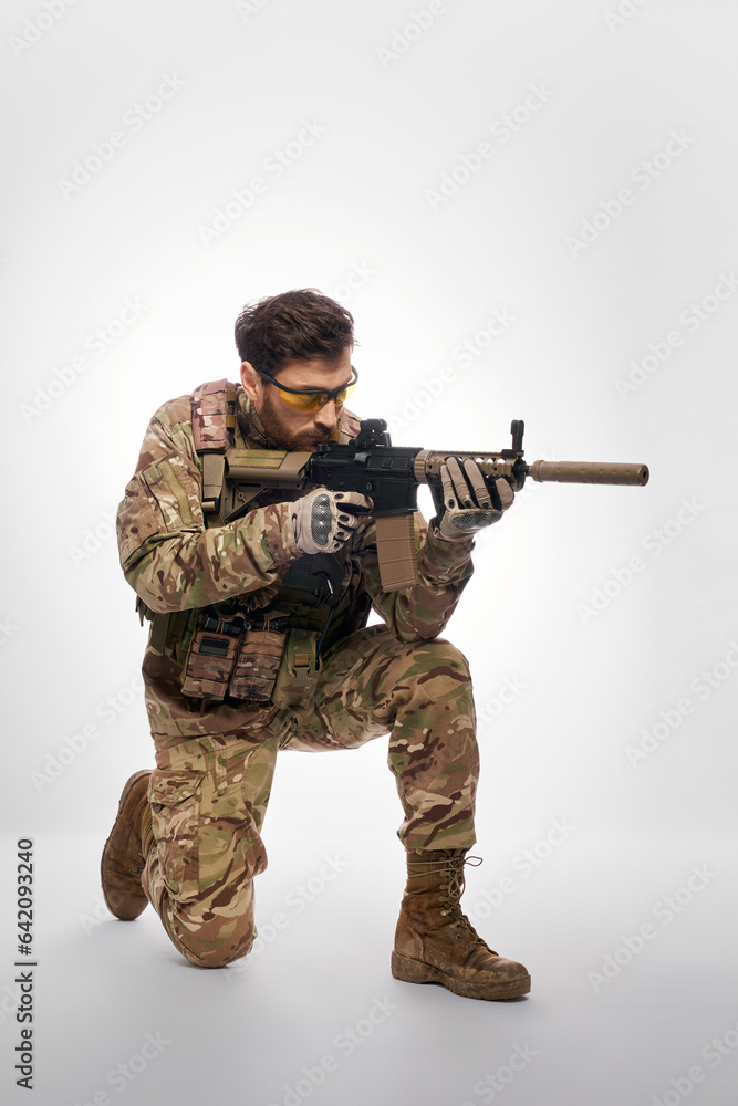 Focused special operations fighter aiming from assault rifle indoors ...