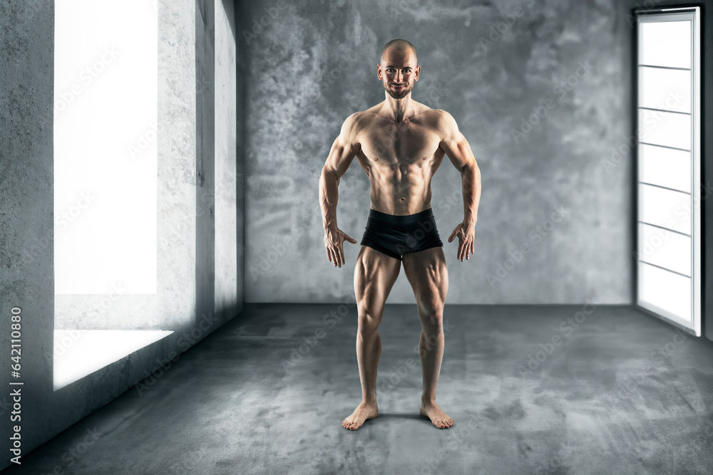 confident bodybuilder stand in concrete room with windows on left and ...